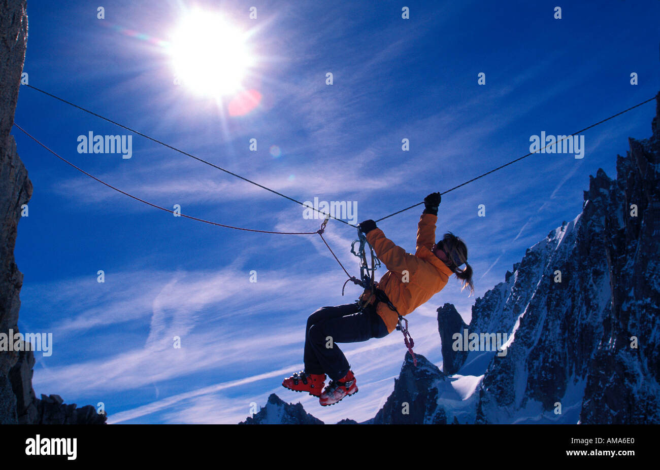 Woman climber hanging from a rope high above a ravine between two ...