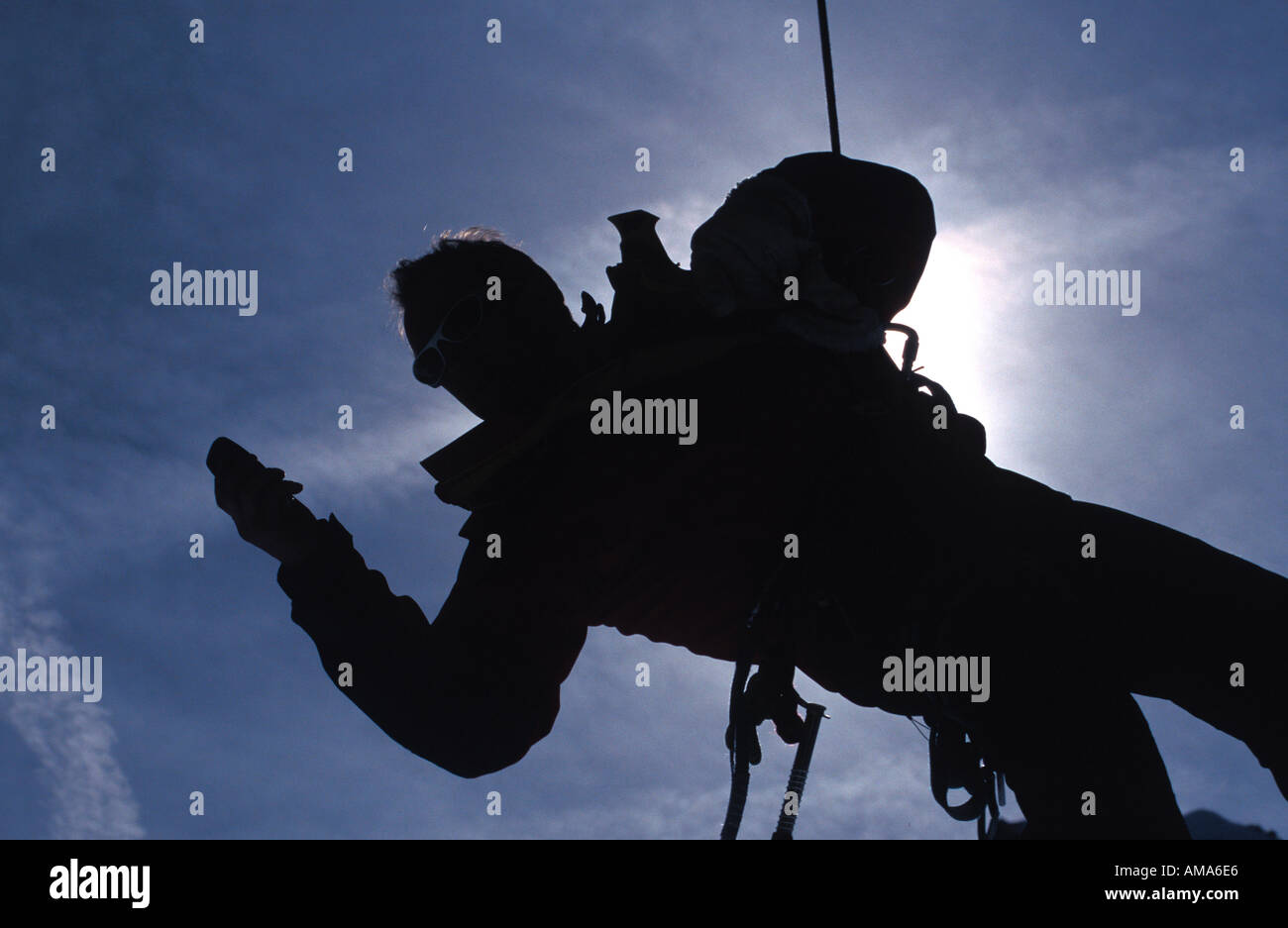 man on a rope hanging about waiting for a call on his mobile phone ...