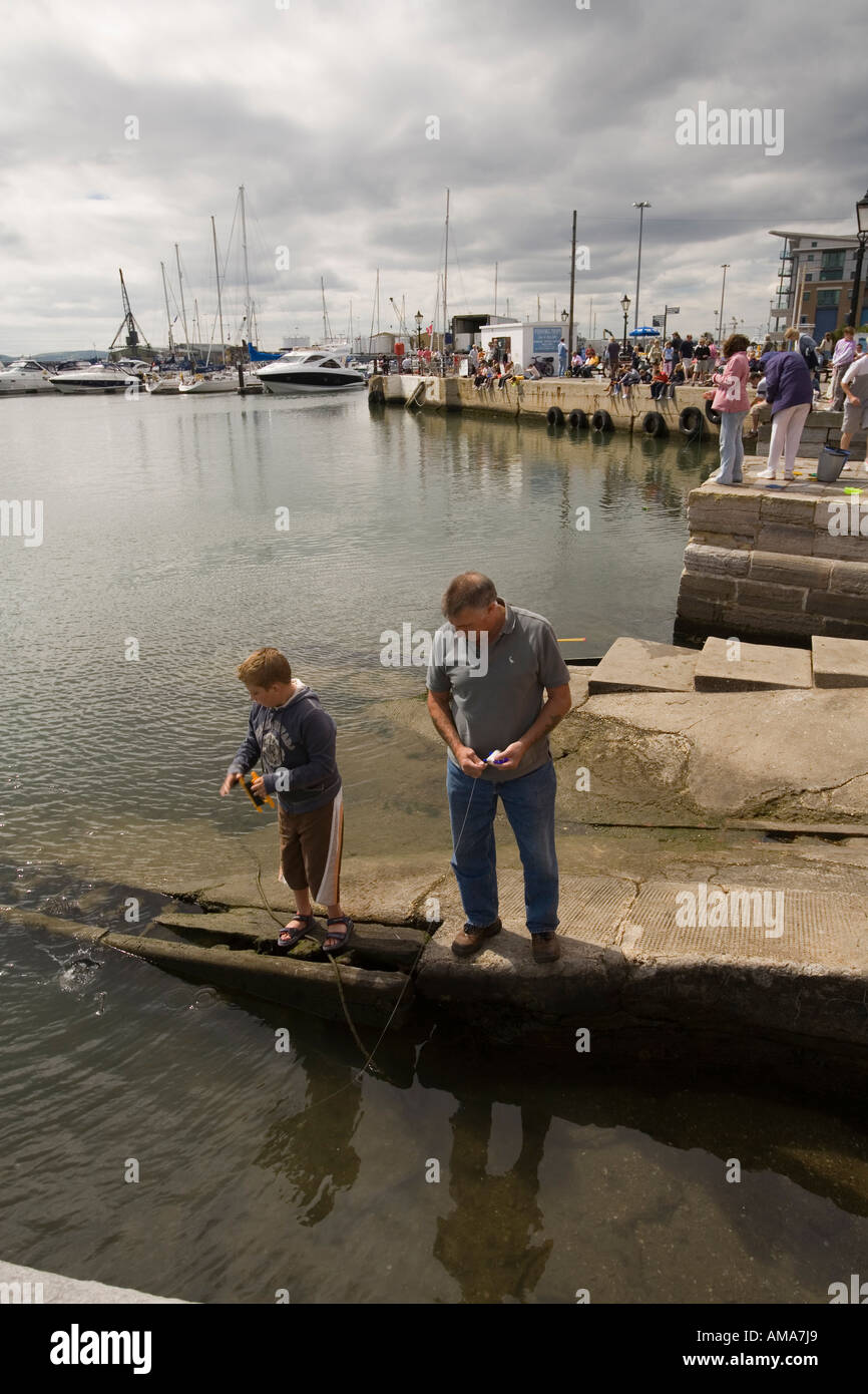 UK Dorset Poole Old Town father and son fishing for crabs from the old ...