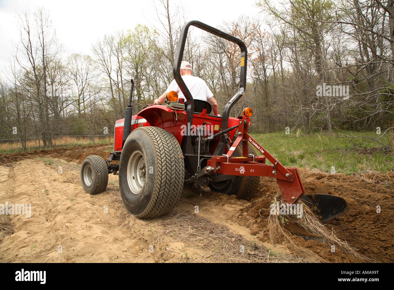 Man driving a small tractor ploughing or plowing field on specialist ...