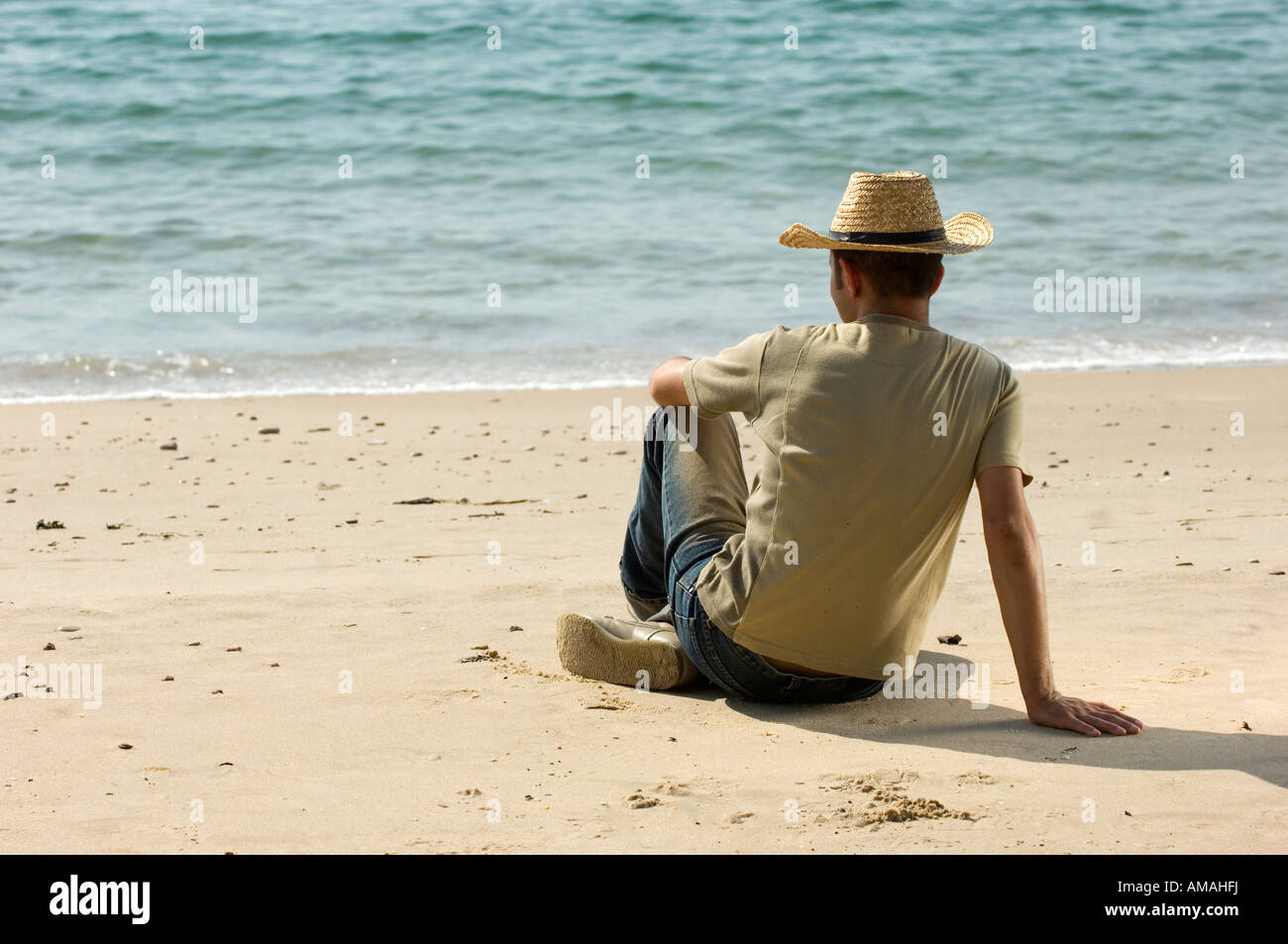 Rare view of a young man wearing cowboy hat sitting on the beach Stock ...