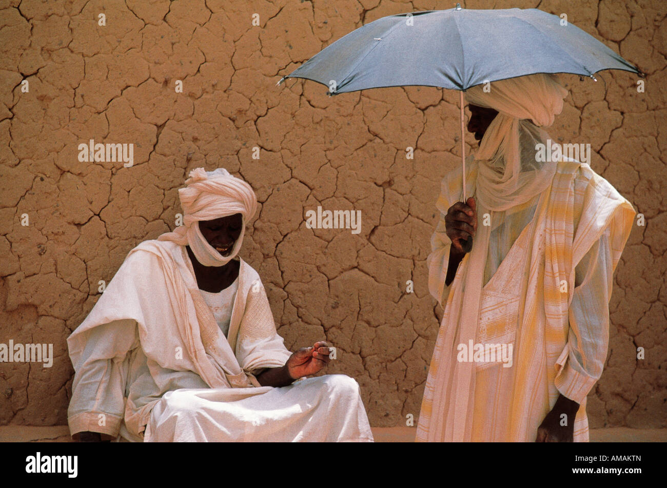 Two men in traditional white robes and turbans chatting outside an ...
