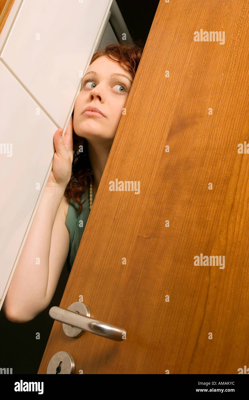 Woman peeking through door hi-res stock photography and images - Alamy