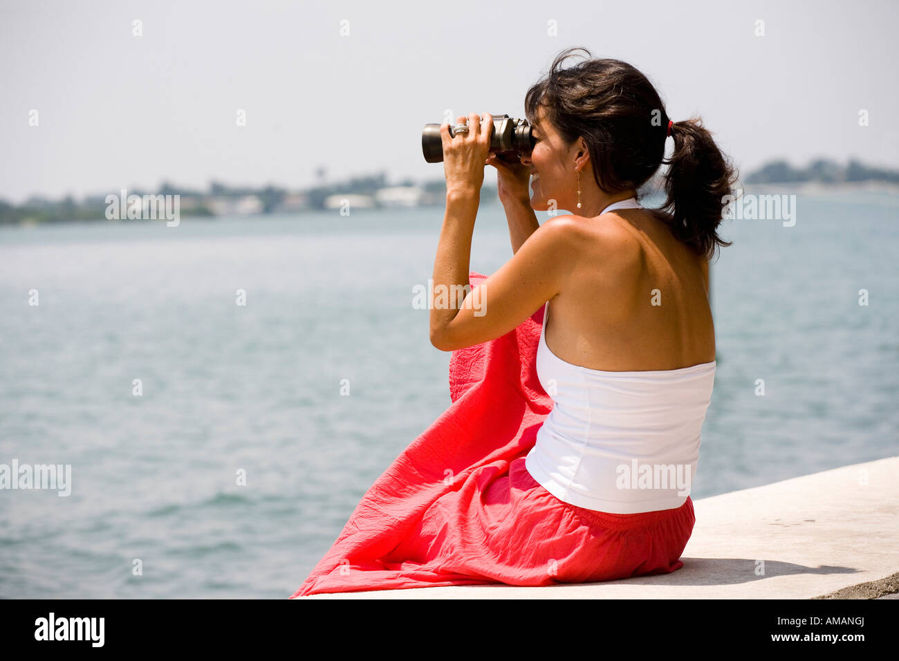 Side view of a woman using binoculars by the sea Stock Photo - Alamy