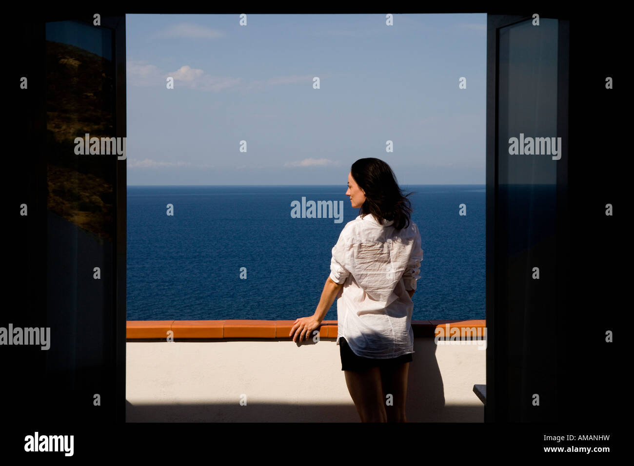 A woman standing on a balcony looking out to sea Stock Photo - Alamy