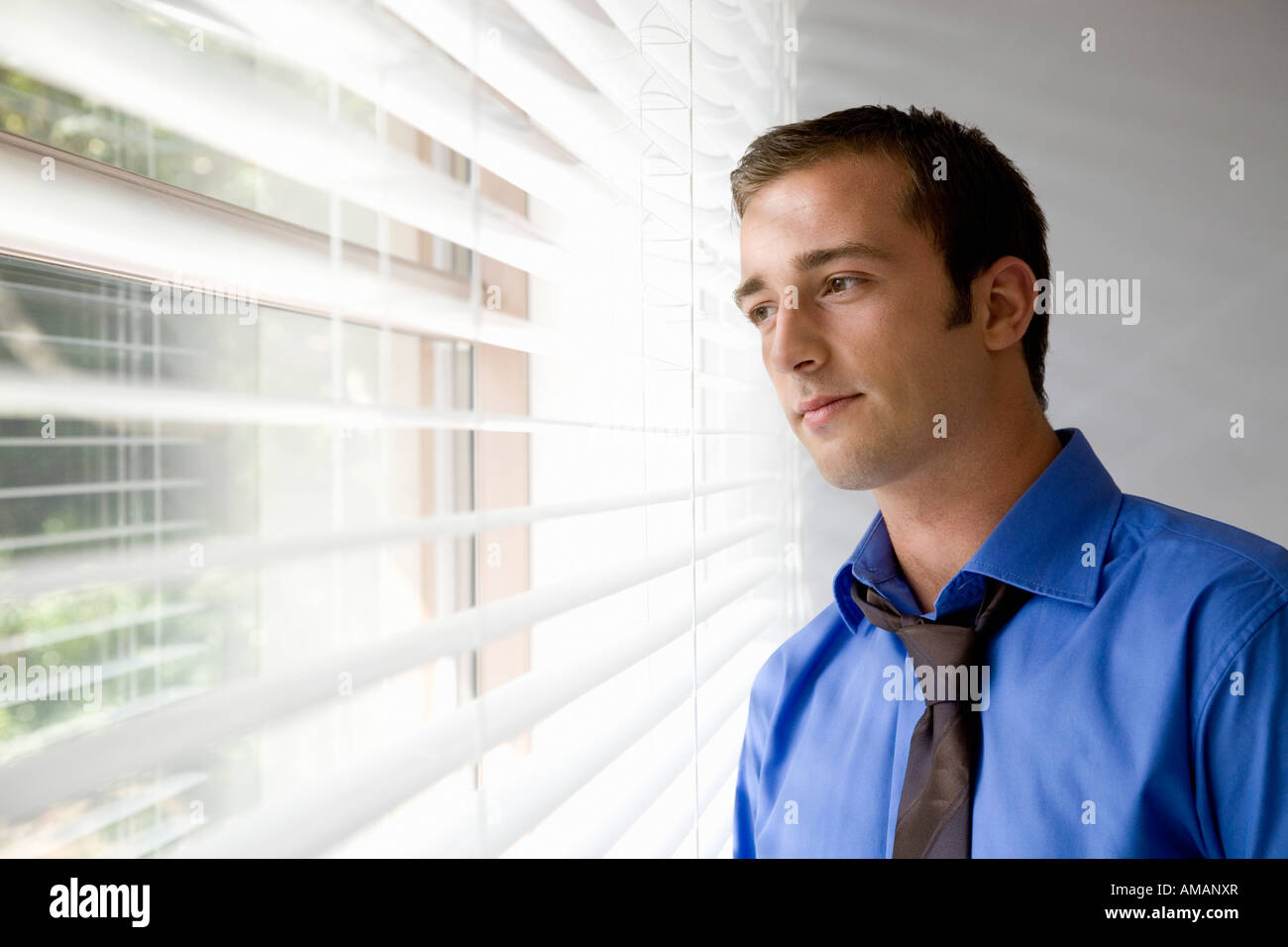 A young businessman staring out a window Stock Photo - Alamy