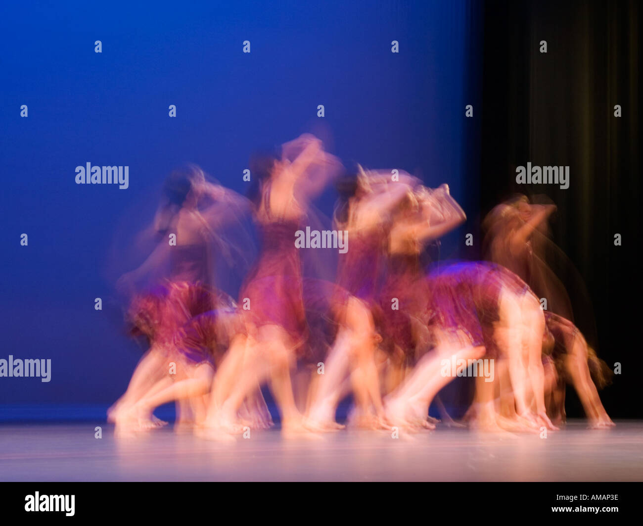 Group of dancers in rich ruby dresses on stage curving together in one ...