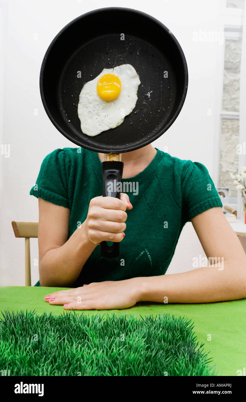 A woman holding a frying pan in front of her face Stock Photo - Alamy