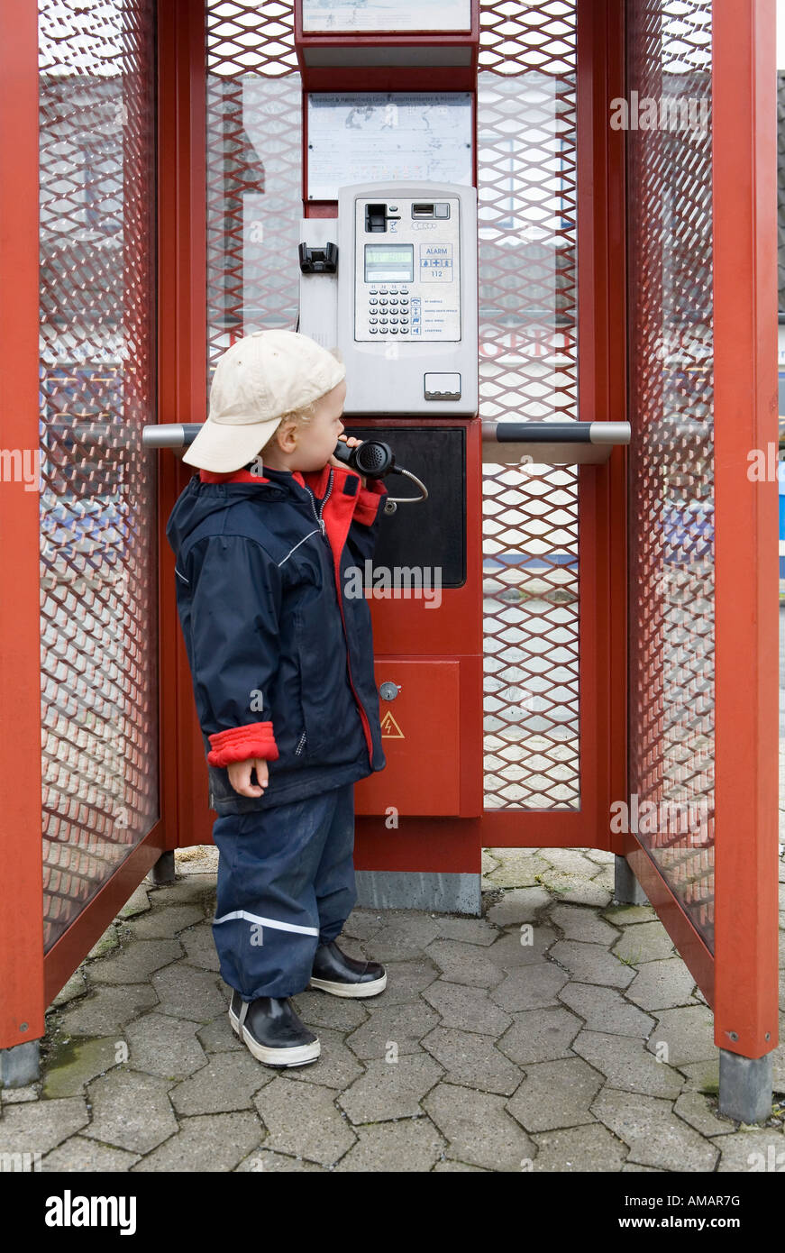 A young boy using a public telephone Stock Photo - Alamy