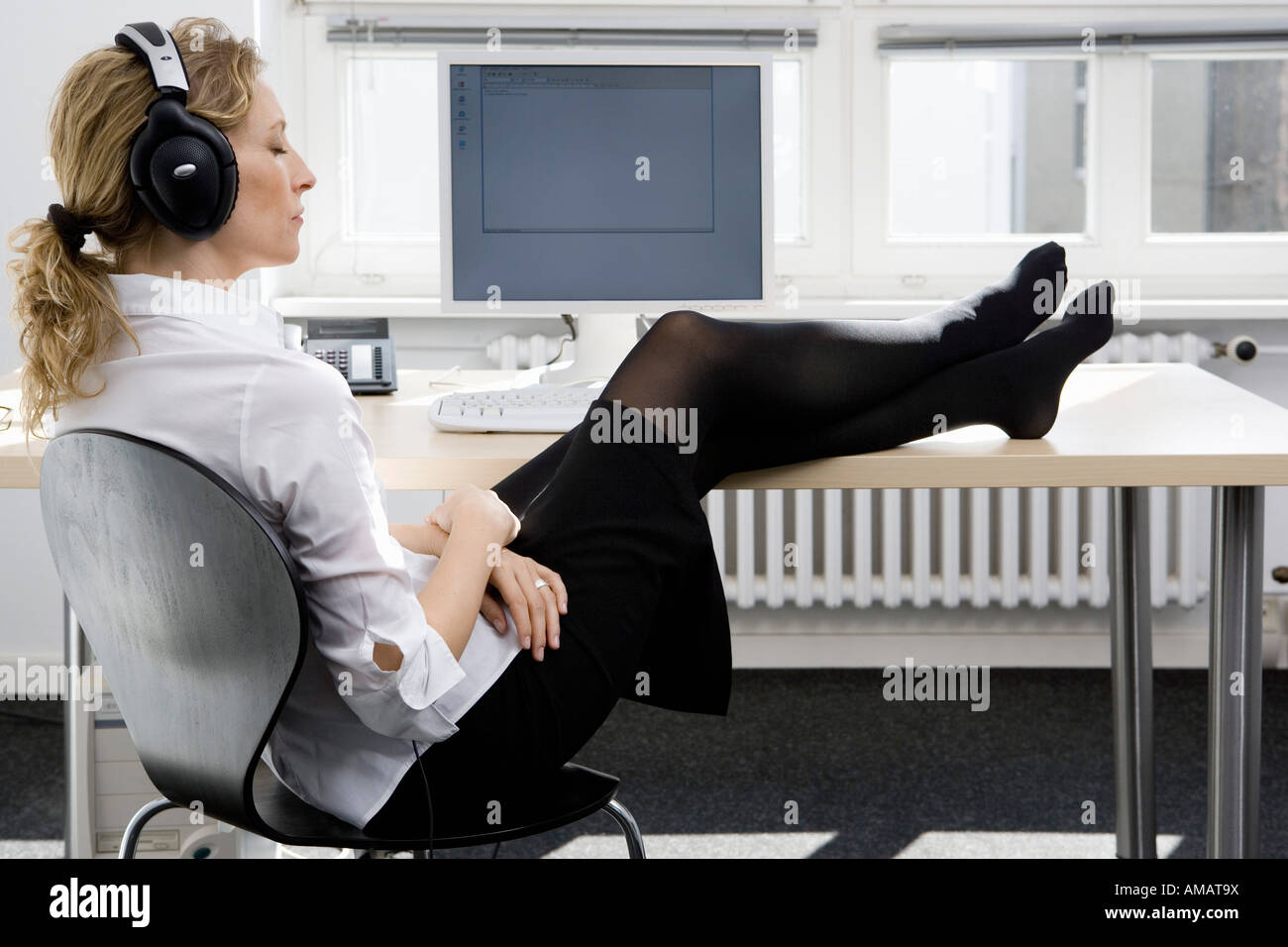 A woman listening to music at work Stock Photo - Alamy