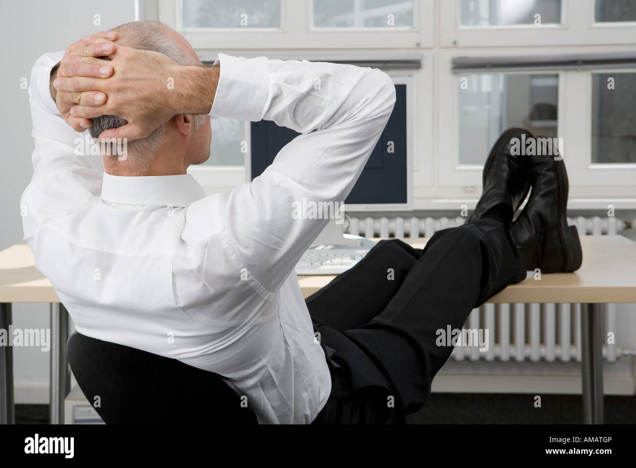 A man sitting with his feet up on a desk Stock Photo - Alamy