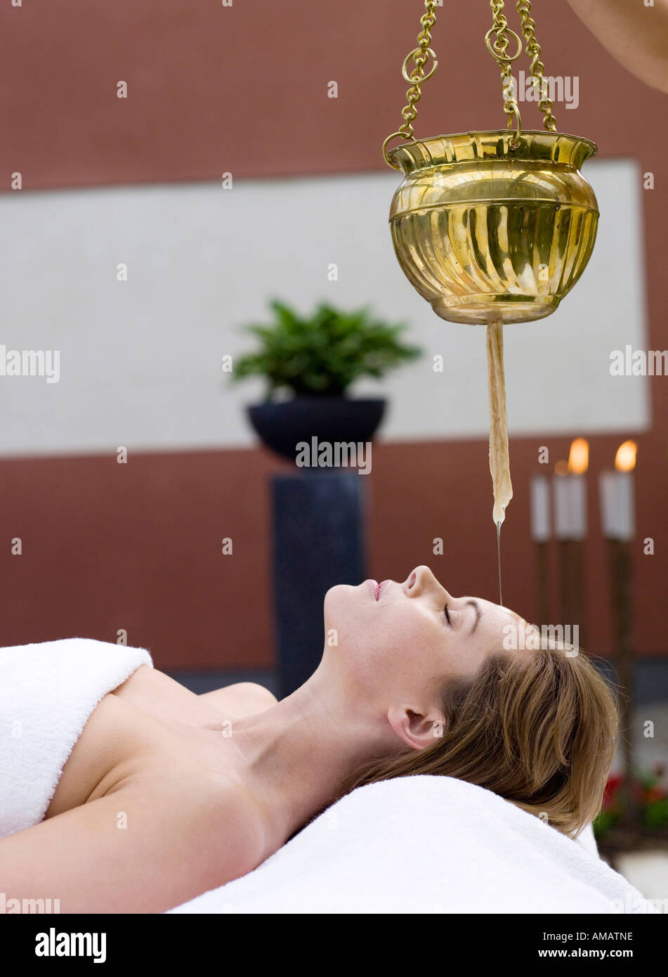 Young woman in spa with oil being poured on forehead, side view Stock ...