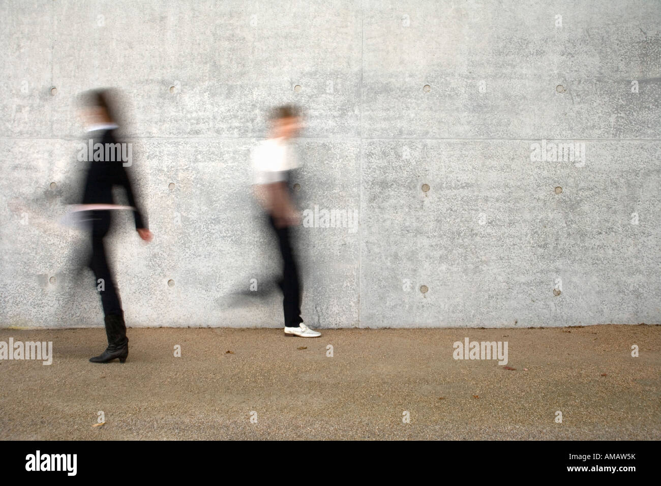 Two people walking past a wall Stock Photo - Alamy