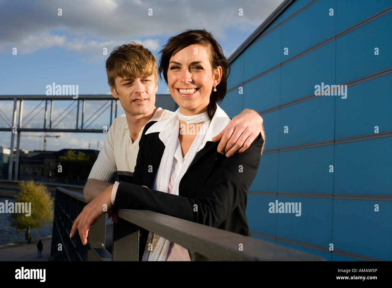 A couple standing next to railings overlooking a river Stock Photo - Alamy