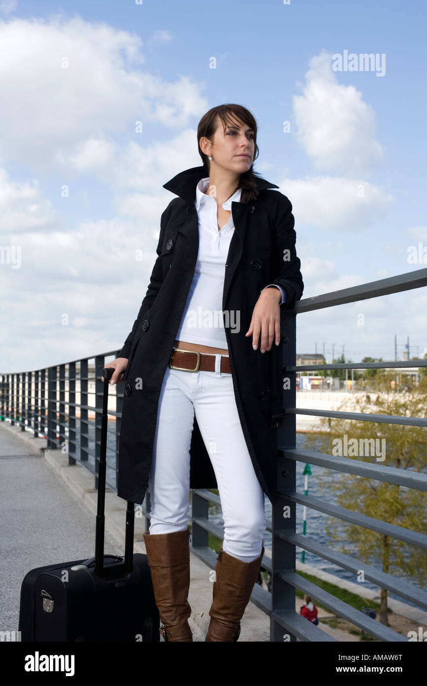 A woman standing on a bridge over a river with luggage Stock Photo - Alamy