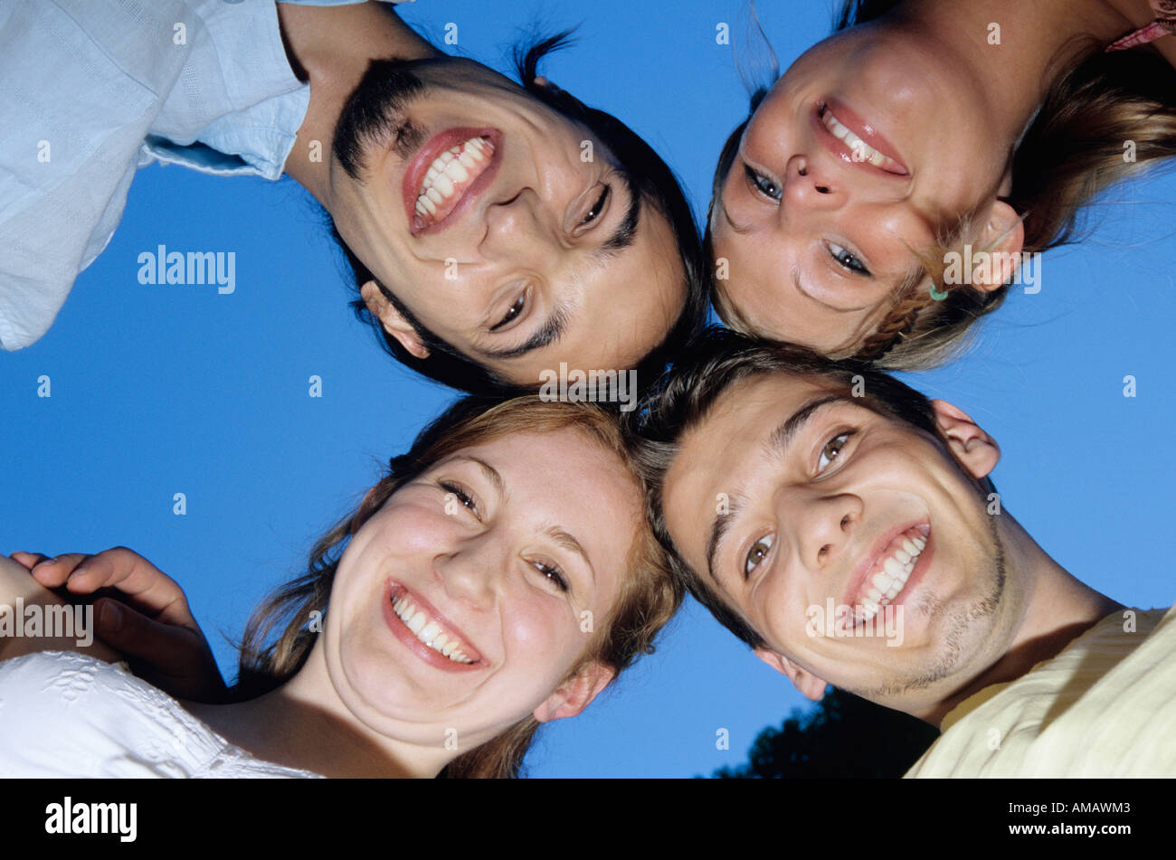 Four young people in huddle, upward view, portrait Stock Photo - Alamy