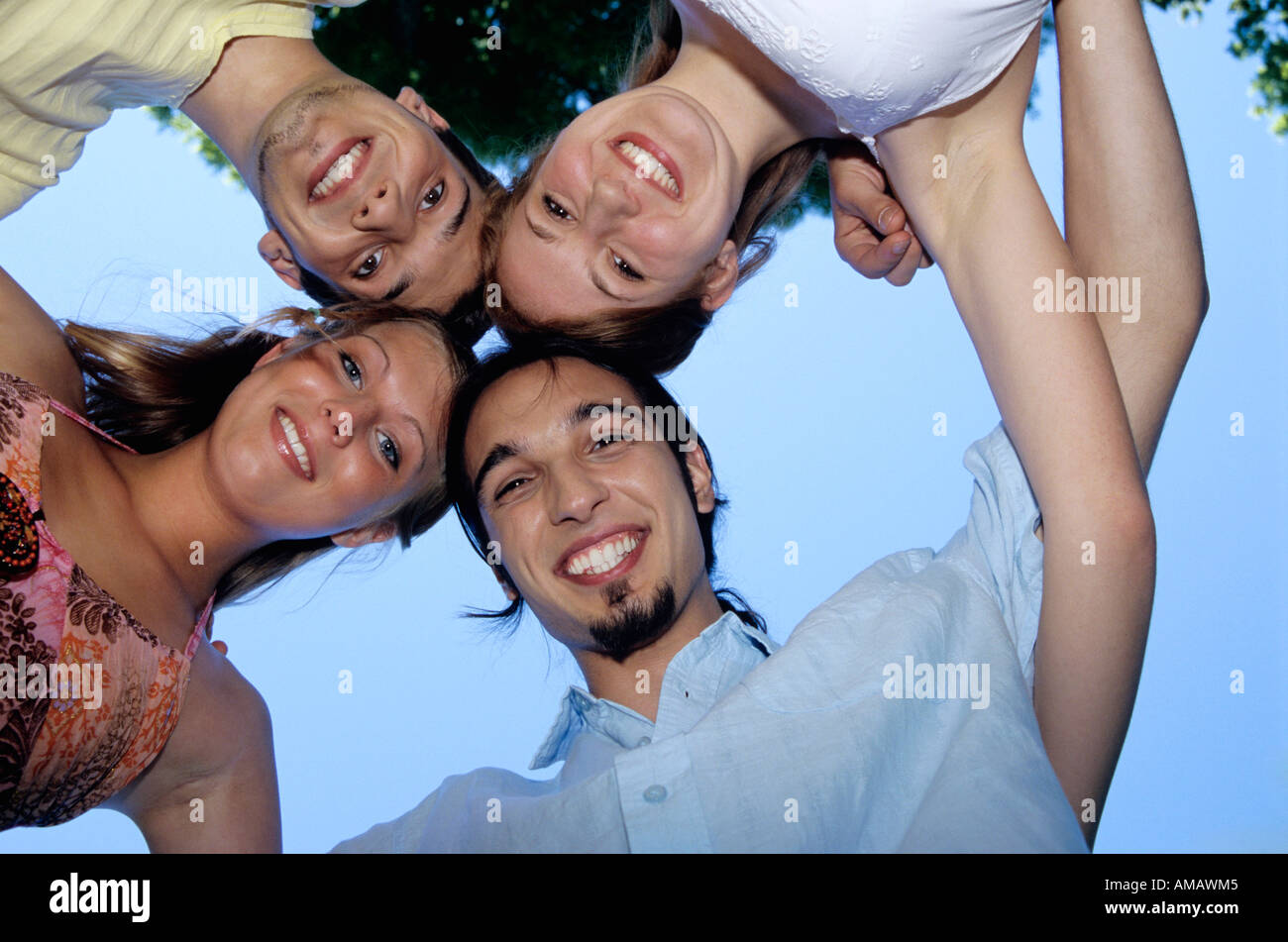 Four young people in huddle, upward view, portrait Stock Photo - Alamy