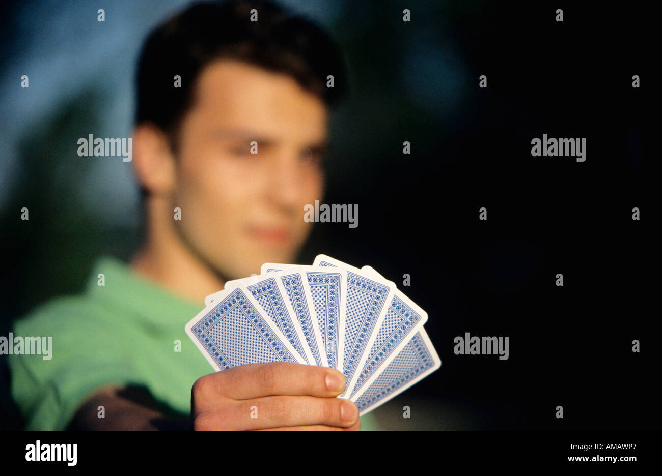 Young man holding playing cards, focus on cards at foreground, close-up ...