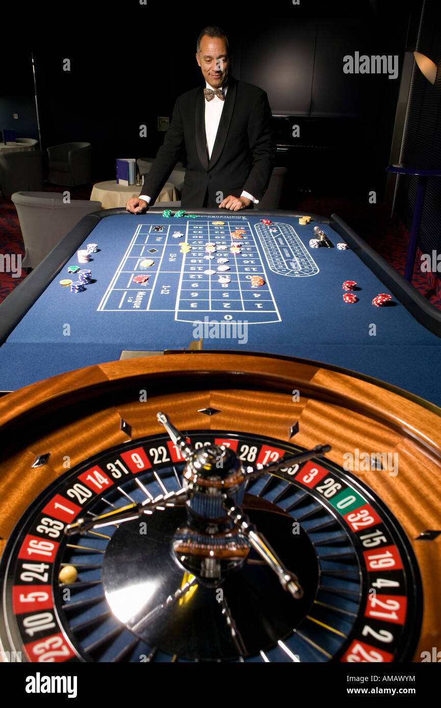 Well dressed man standing at roulette table Stock Photo - Alamy