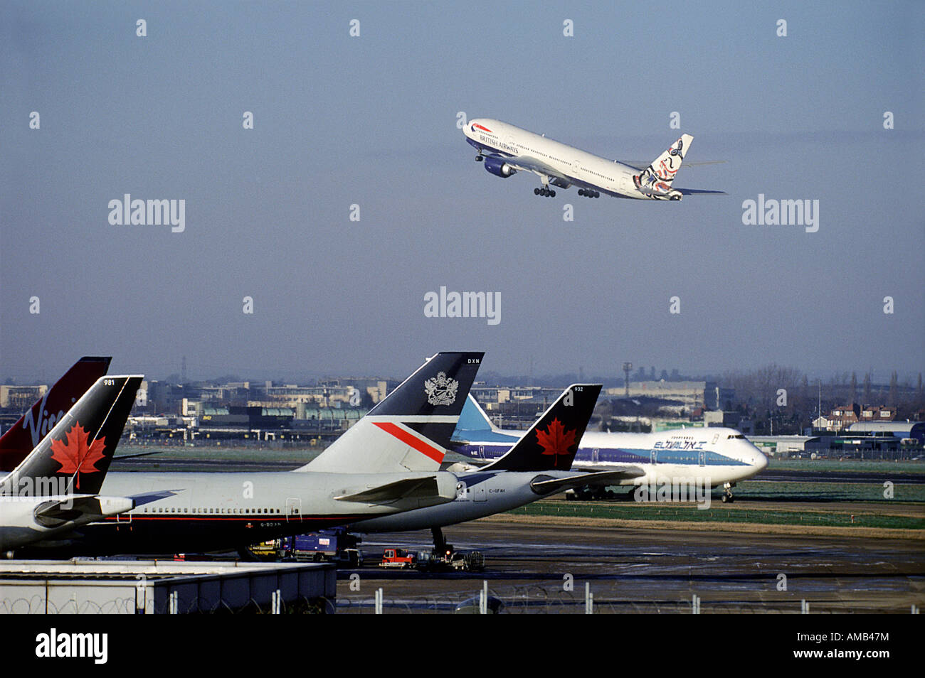 Heathrow airport with parked planes and a plane taking off in the ...