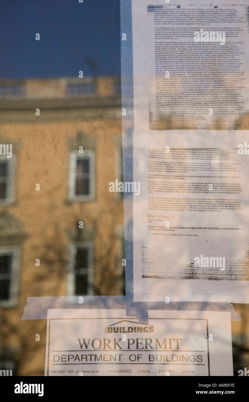 A work permit seen through a door window in which a building reflects ...