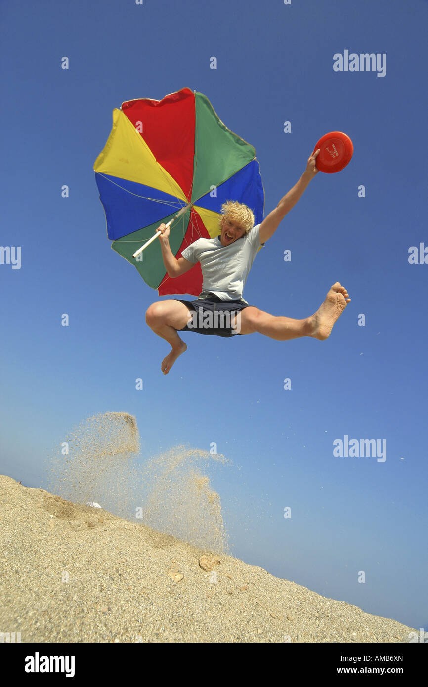 young man with frisbee and sunshade jumping on the beach Stock Photo ...