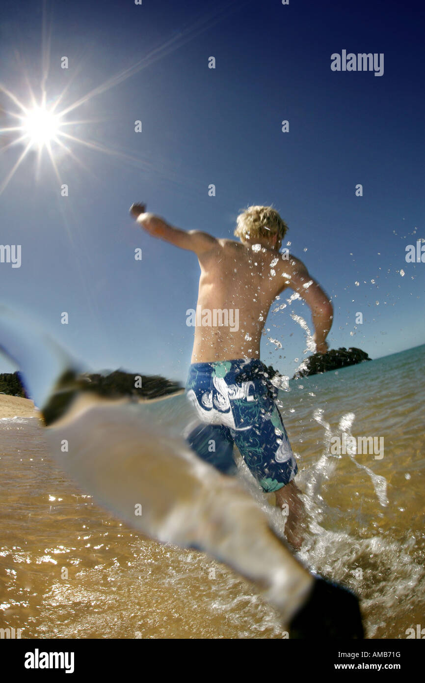 young fair-haired man running through water at the beach Stock Photo ...