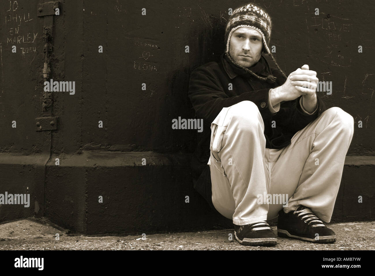 man crouching against a wall Stock Photo - Alamy