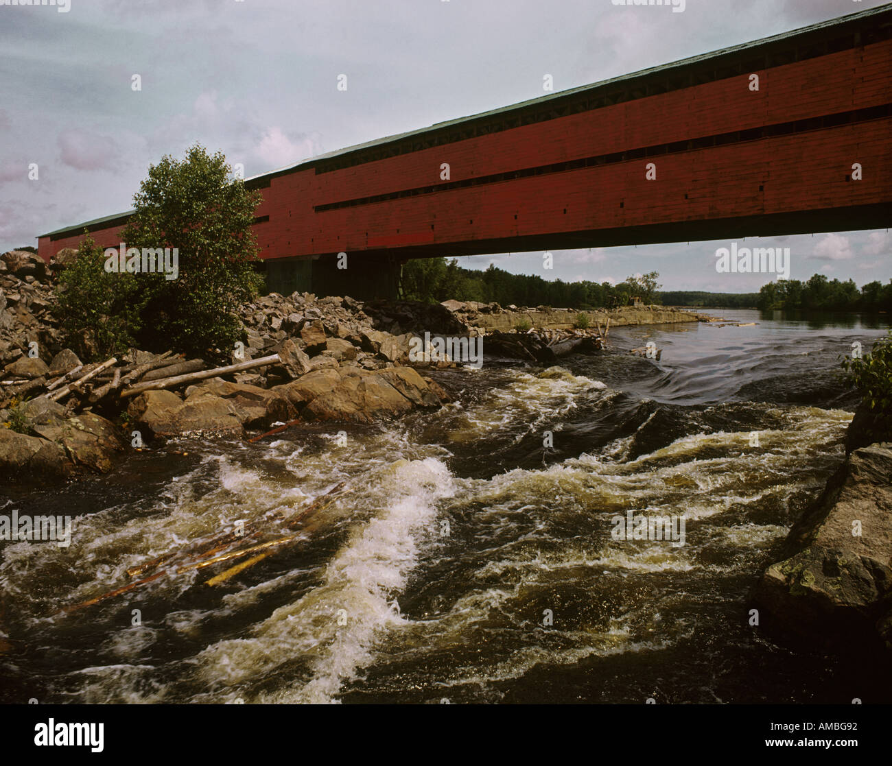 Red covered wooden bridge above fast flowing Gatineau River Quebec ...