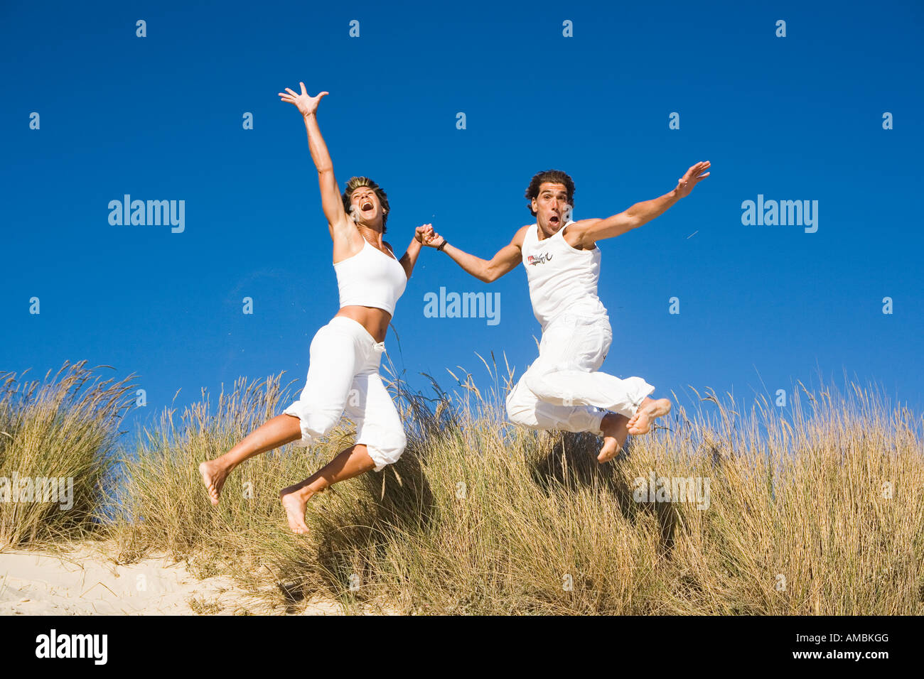 couple holding hands jumping at the beach Stock Photo - Alamy