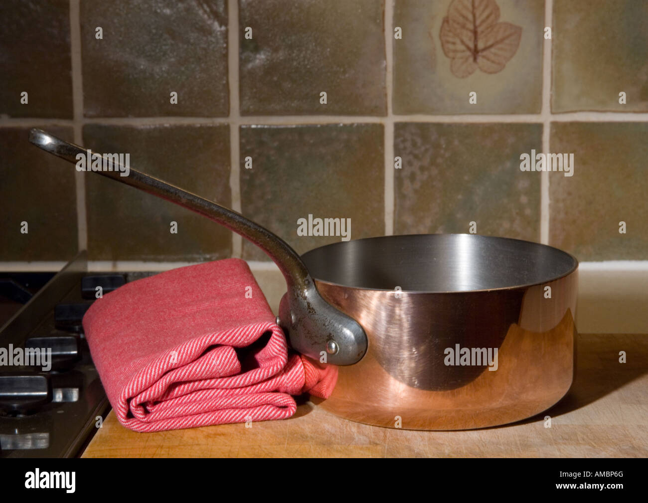 Polished opper pan with red cloth by hob in kitchen Stock Photo - Alamy