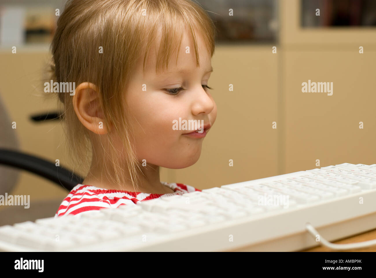 Little girl reaching out and looking to the computer keyboard that ...