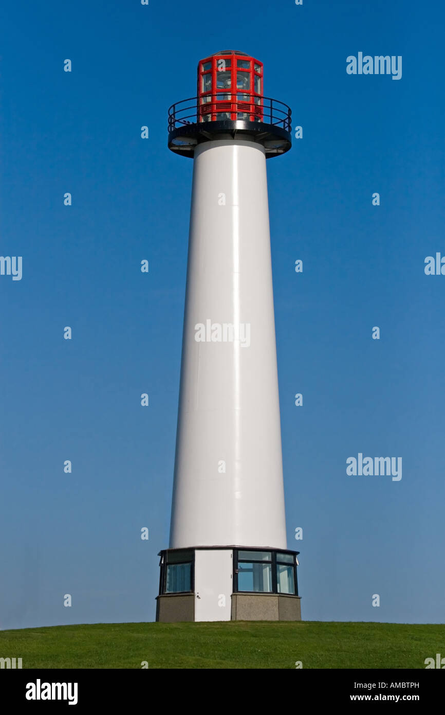 A tall and gleaming white lighthouse at the harbors entrance Stock ...