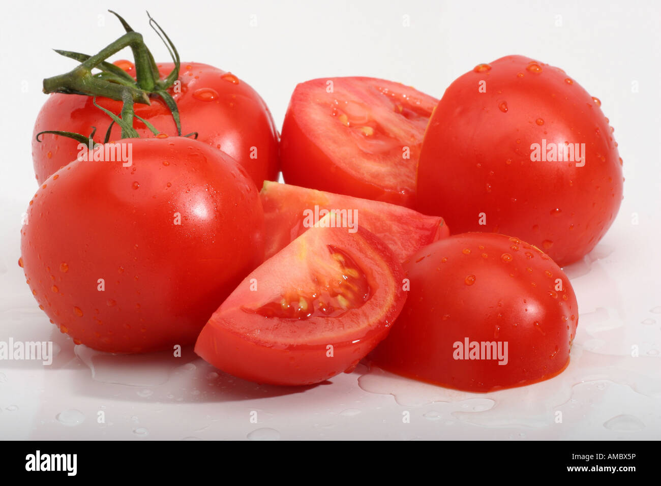 Ripe red cherry tomatoes whole and pieces with water drops cross ...