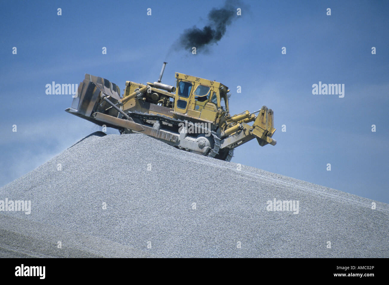 The bulldozer a powerful diesel machine is piling heaps of aggregate at ...