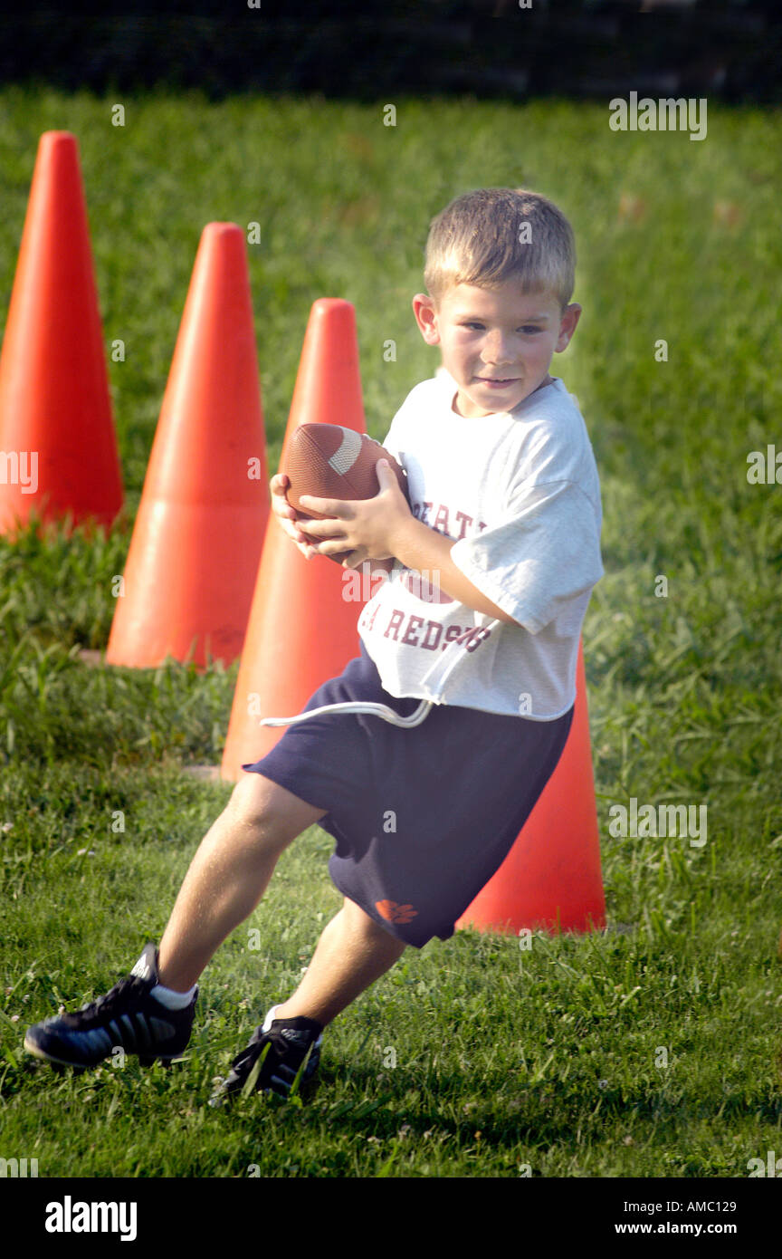 6 Year old boy practicing carrying football around field markers hoping ...