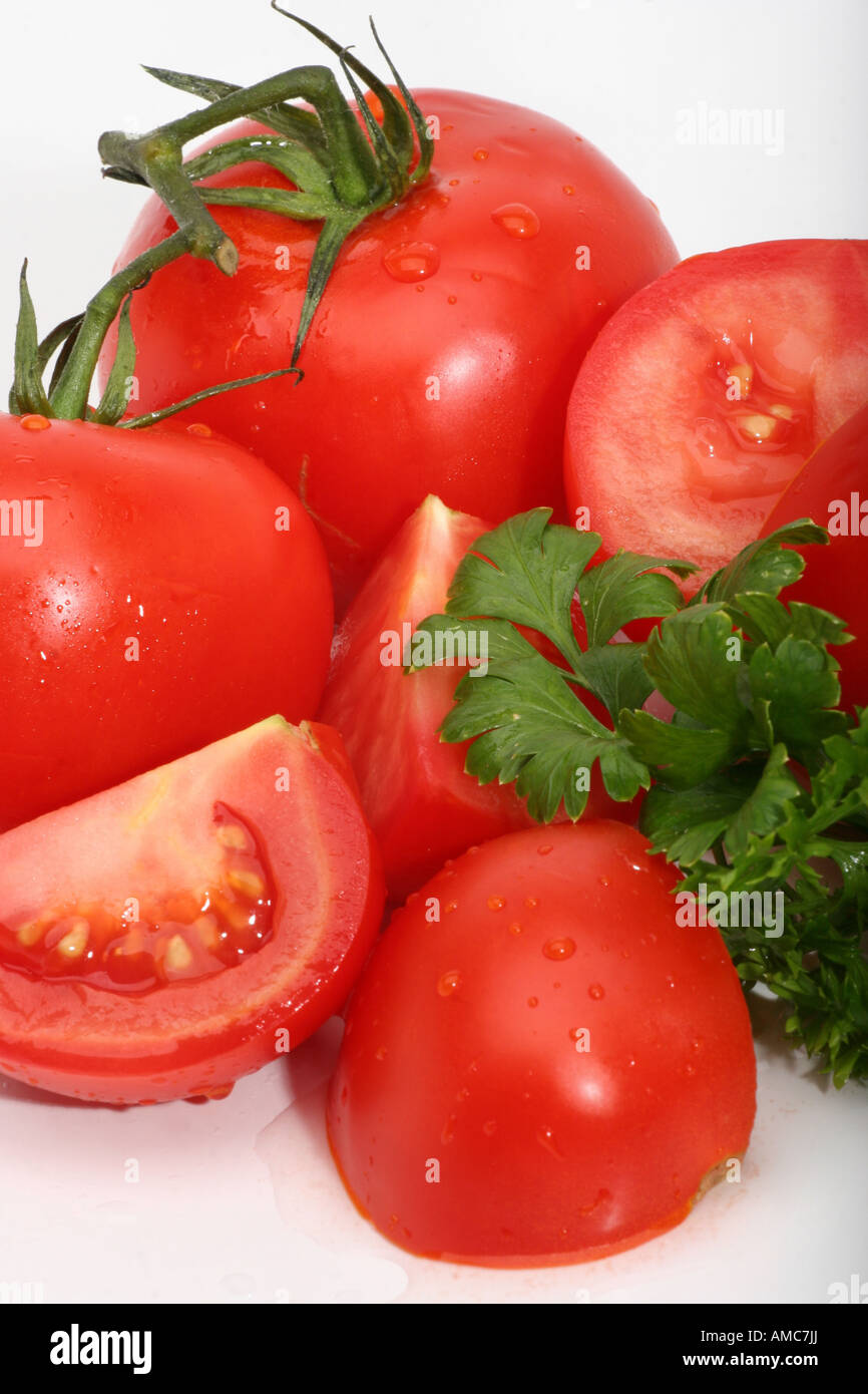 Closeup of organic ripe red tomatoes whole and pieces with water drops cross section from above ...