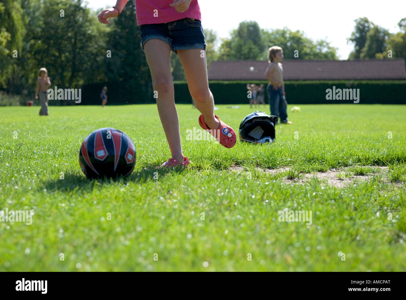 a young girls legs kicking a football approach foreground with small ...