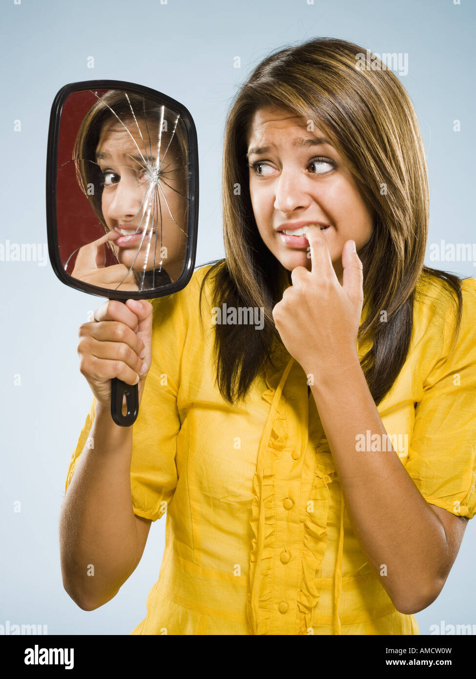 Woman looking into shattered mirror nervously Stock Photo - Alamy