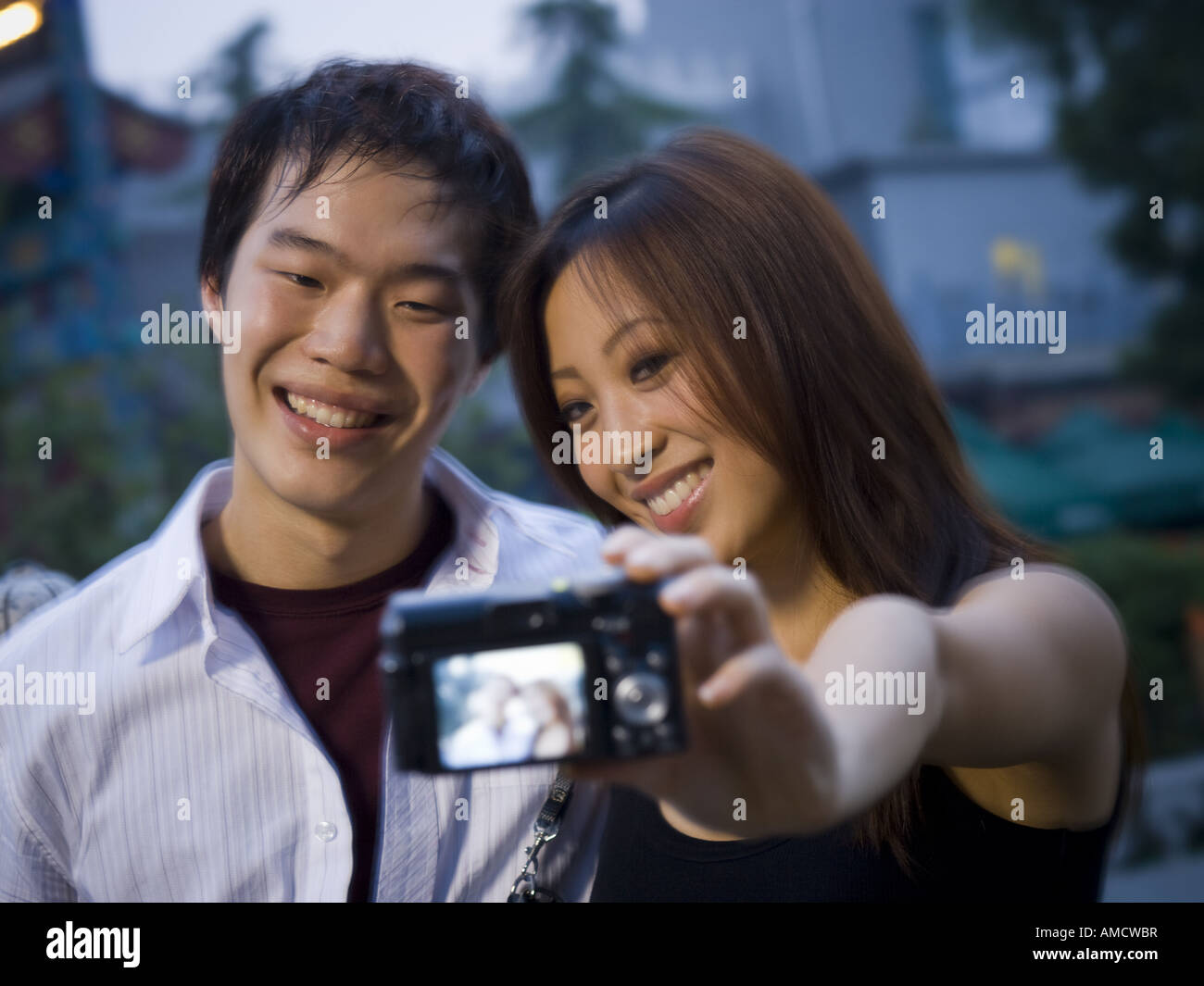 Couple embracing and smiling outdoors with camera Stock Photo - Alamy