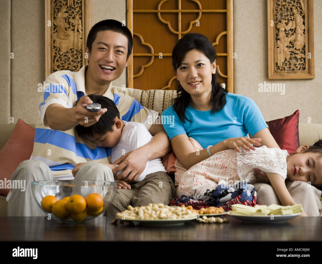Family watching TV with children asleep Stock Photo - Alamy