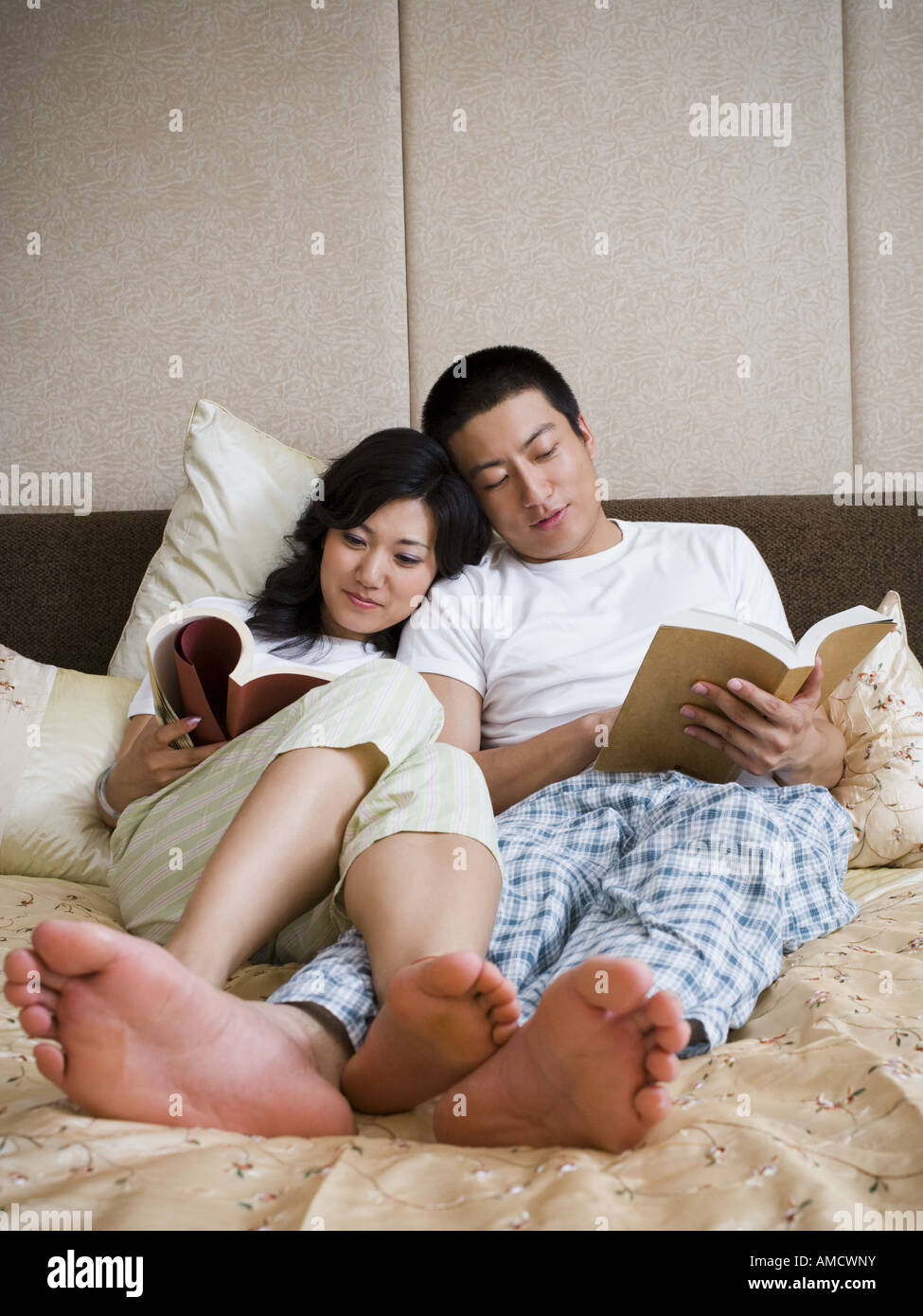 Couple in bed snuggling and reading Stock Photo - Alamy