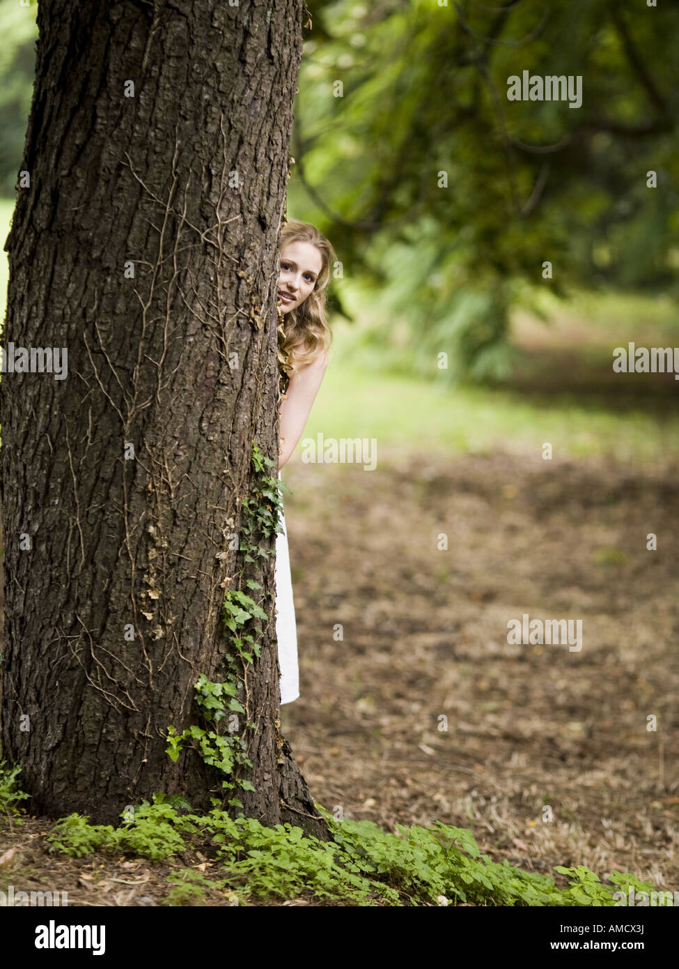 Woman hiding behind tree Stock Photo - Alamy