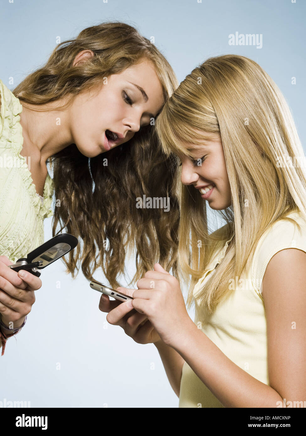 Two girls with cell phones smiling Stock Photo - Alamy