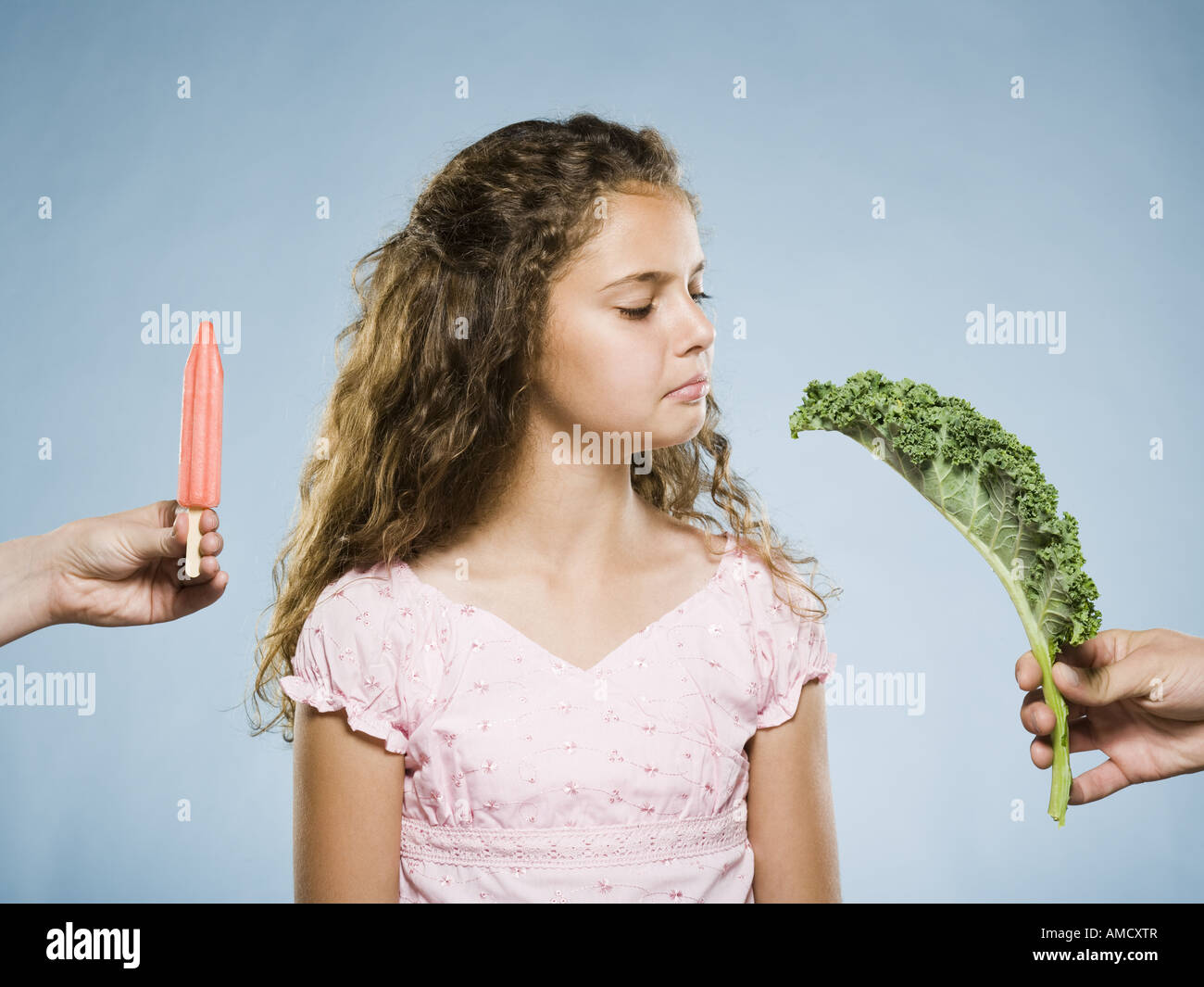 Girl deciding between Popsicle and green leafy vegetable Stock Photo ...