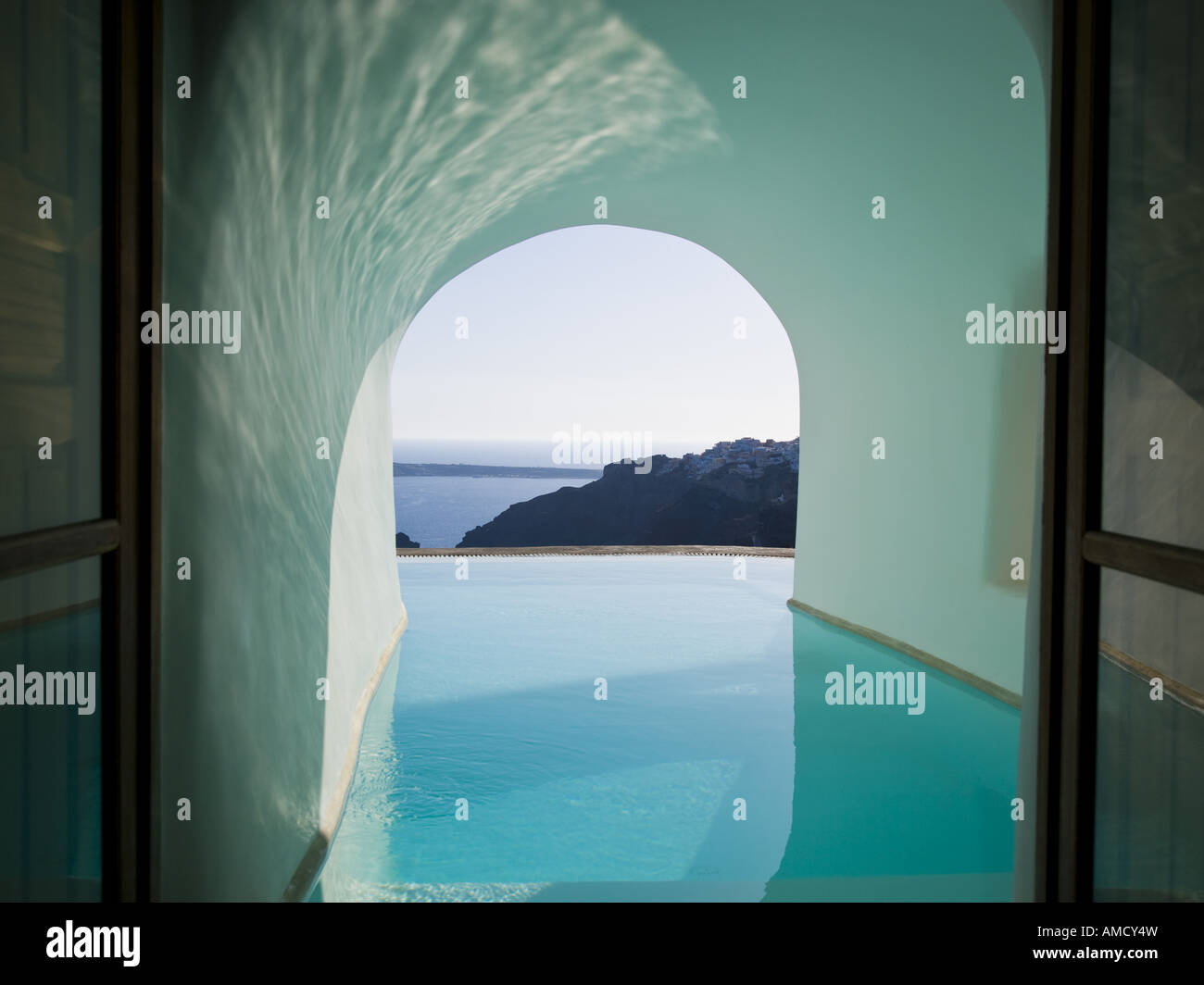 View of infinity pool through archway with mountains and water Stock ...
