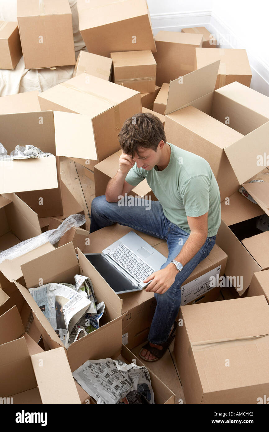 Man Sitting amongst Moving Boxes with Laptop Computer Stock Photo - Alamy