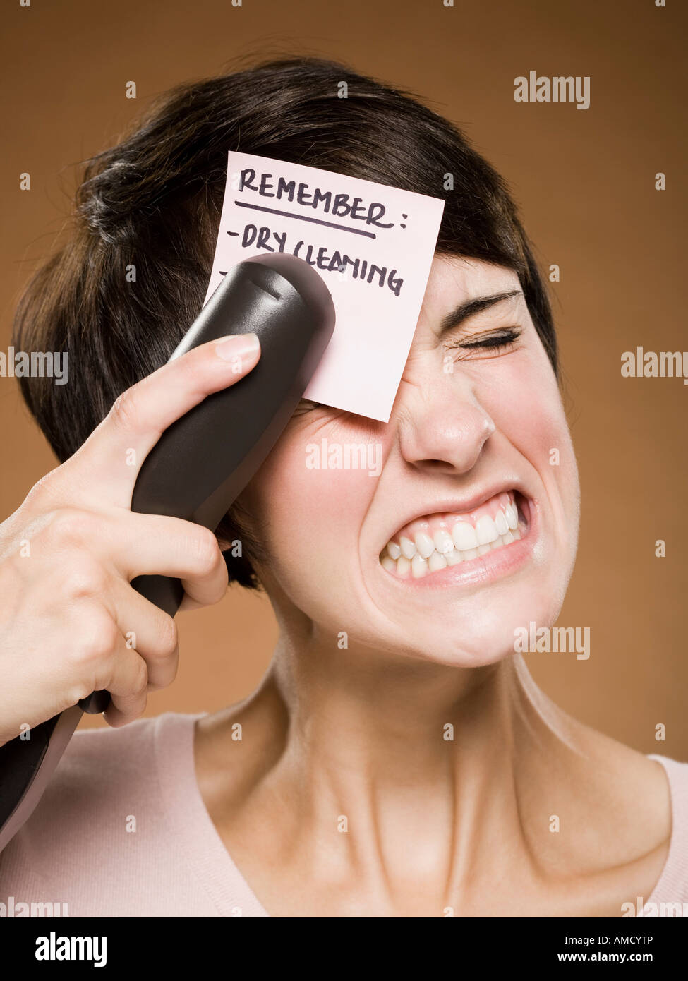 Woman stapling list of things to remember to her forehead and wincing ...