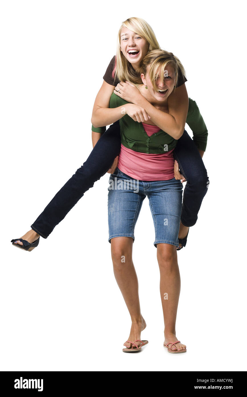 Two teenage girls laughing and giving piggy back ride Stock Photo - Alamy