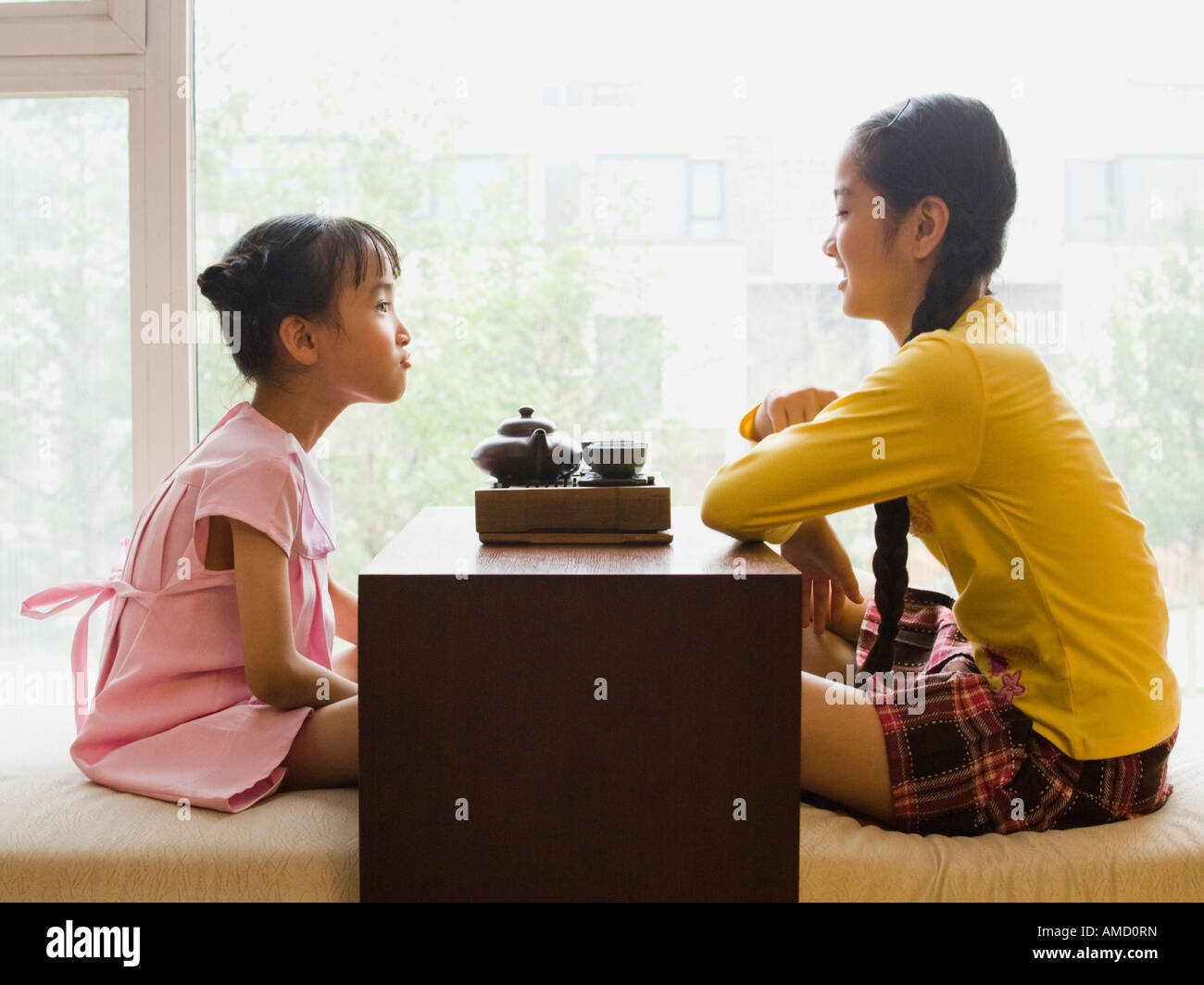 Profile of two girls sitting cross legged having tea Stock Photo - Alamy